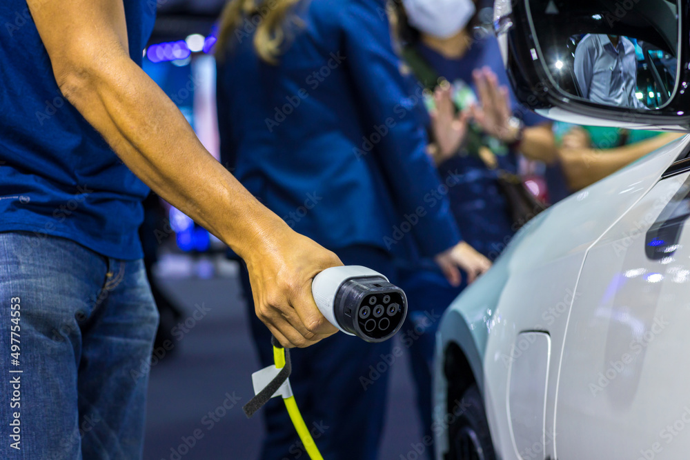 Hand holding Electric car charger. Electric Vehicle EV Charging station ...