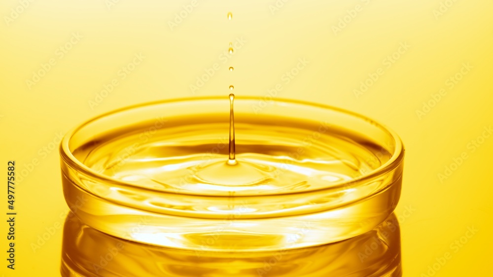 Drop of water falls down into petri dish with clear fluid creating ...