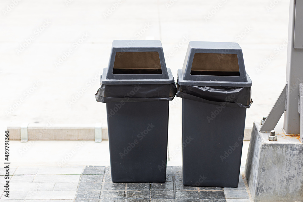 Separation of waste Two black trash cans are placed in a public place ...