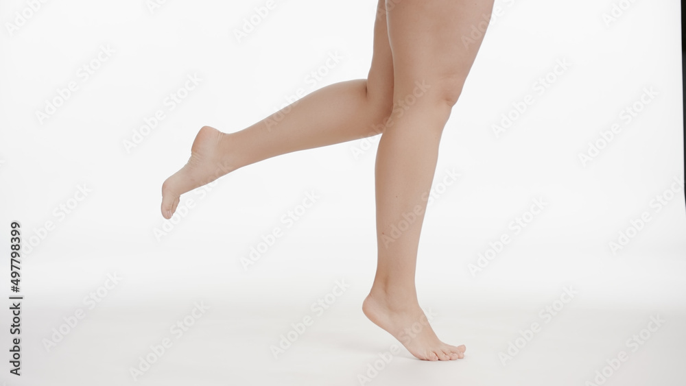 White-skinned plus size woman stands on her tiptoes and bends her leg ...