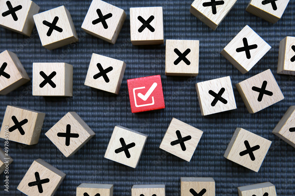 Close-up check mark on cube wooden toy block stack with cross symbol ...