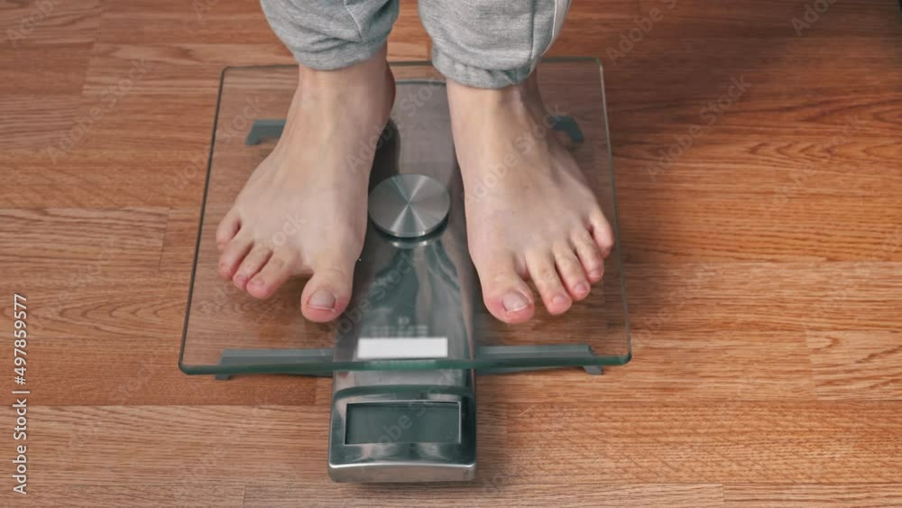 Women's feet stand on the scales and check their kilograms top view ...