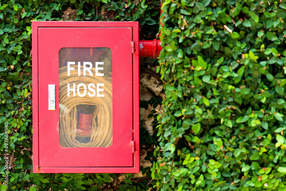 Red fire hose hangs on a stone wall in an exotic hotel. Fire ...