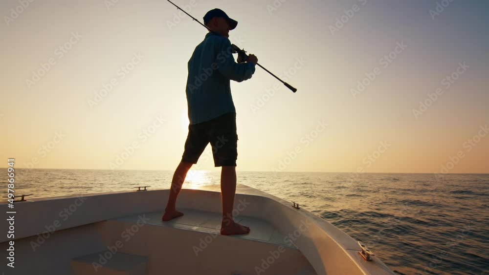 Open sea fishing. Angler stands with fishing rod on the boat floating ...