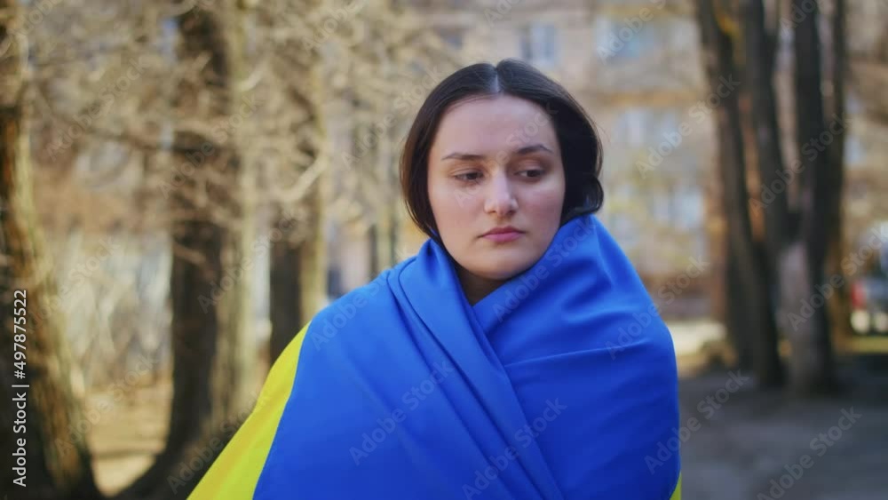 Portrait of a sad Ukrainian woman with a Ukrainian flag and a sign. The ...