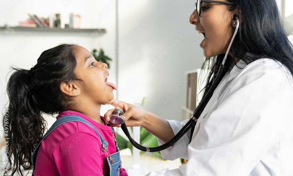 Indian female doctor examining a cute little girl with a stethoscope ...
