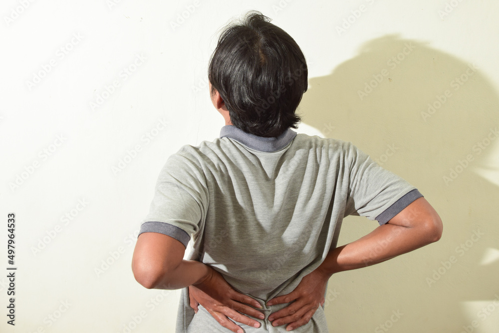 portrait of asian man groaning in pain while holding his back waist ...