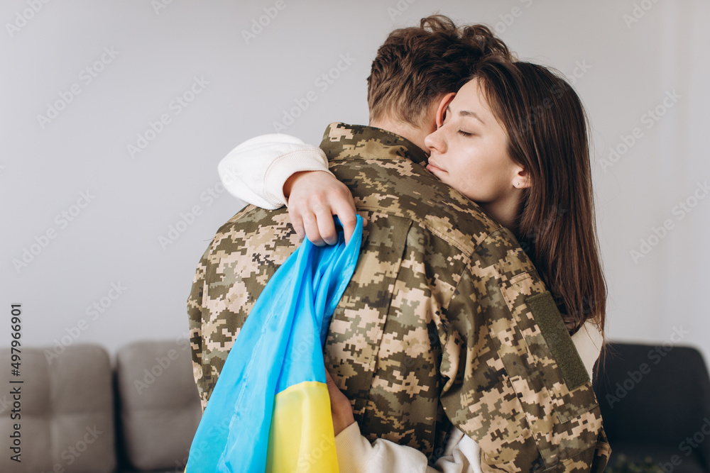 A Ukrainian girl hugs and holds a yellow and blue flag of a military ...