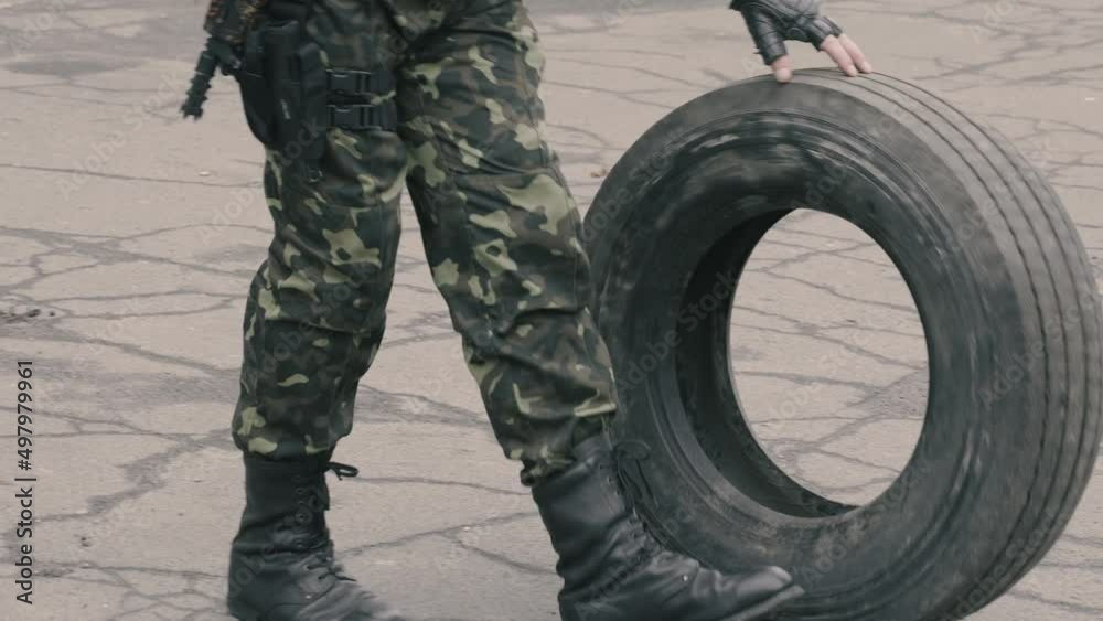 close-up. military feet shod in heavy army boots. old car tires ...