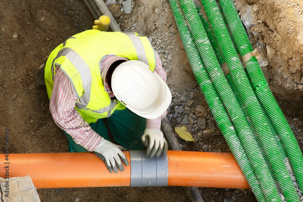 worker installing hdpe corrugated electric and sewer pipes at the ...