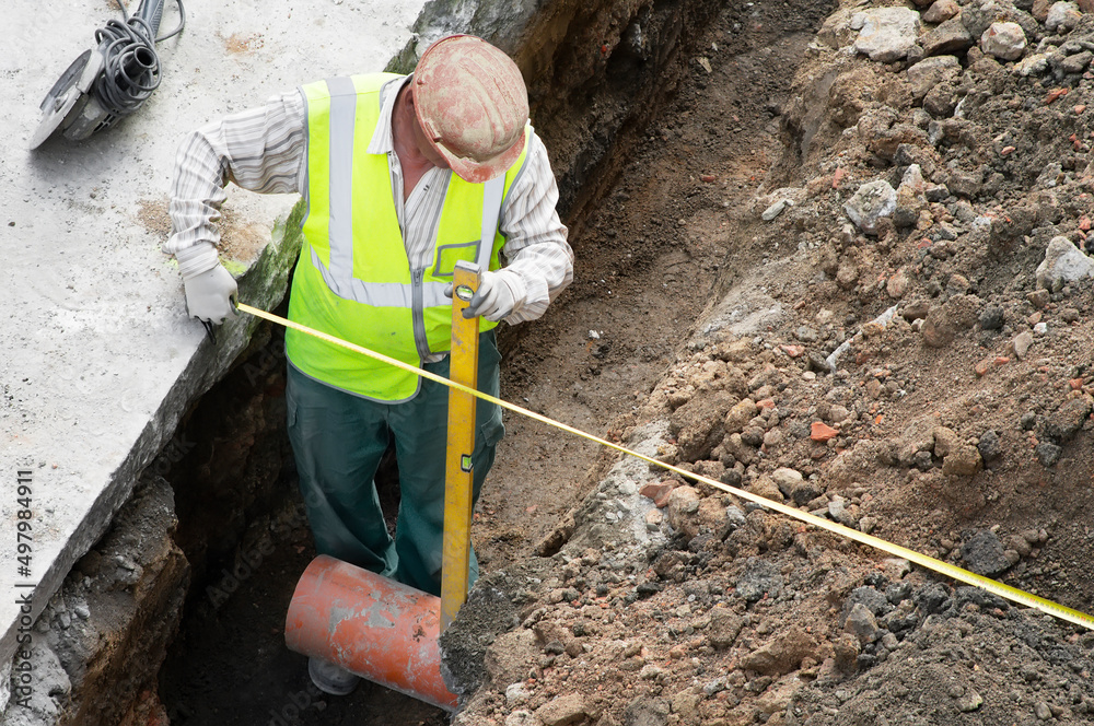 construction worker with a tape measure takes measurements for the ...