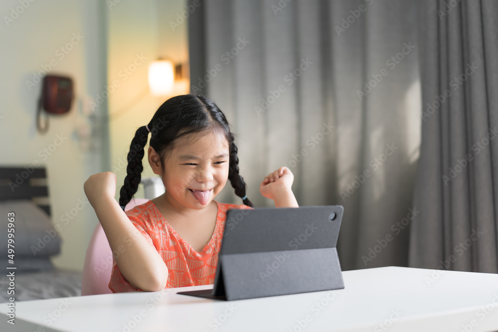 asian child smile stick out tongue to learning on computer tablet or ...