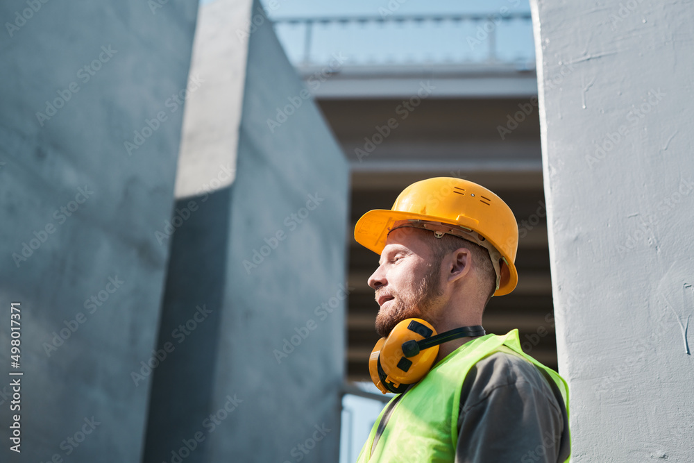 Construction worker wearing hardhat standing on roof of unfinished ...