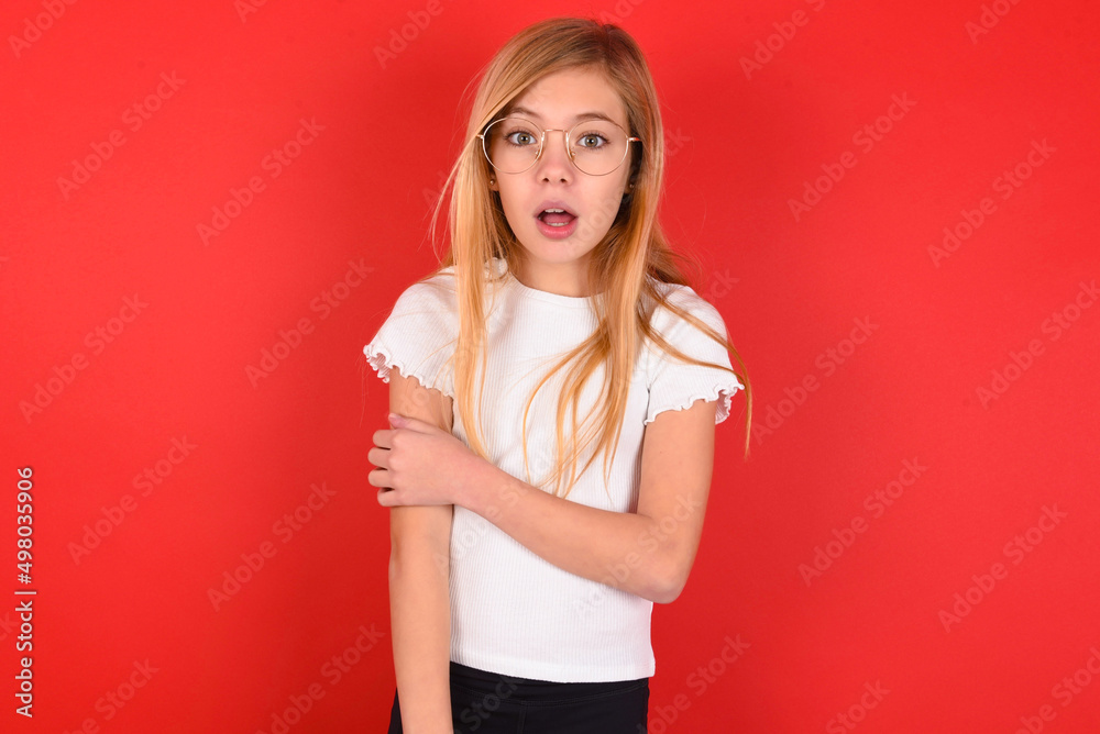 Shocked embarrassed blonde little kid girl wearing white t-shirt over ...