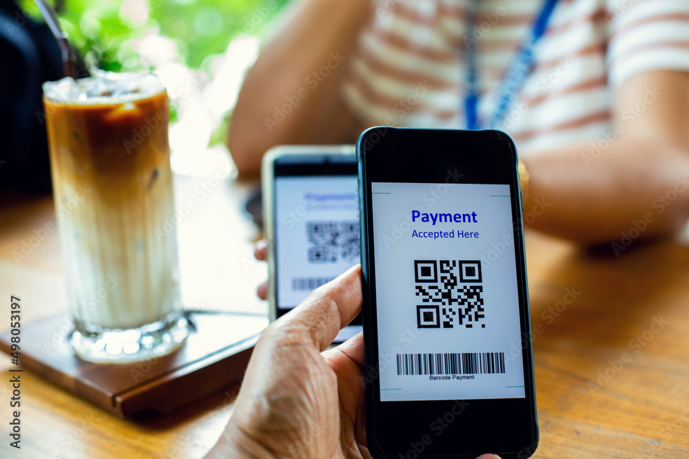 Smartphone in hand to scan QR code payment tag and blurry ice coffee ...