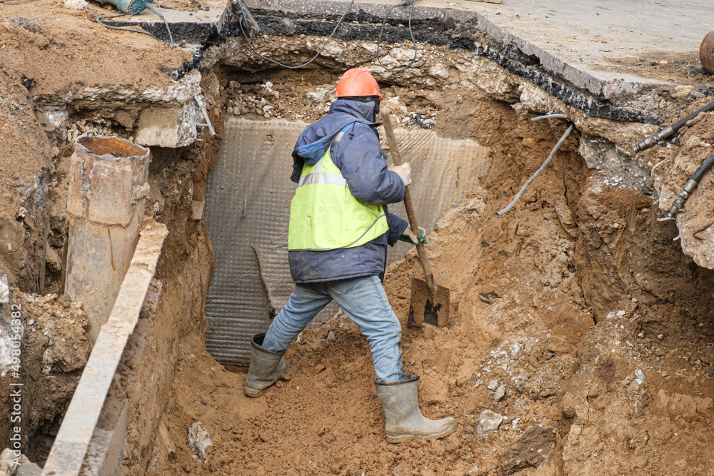 Man dressed as worker and wearing construction helmet is digging a ...