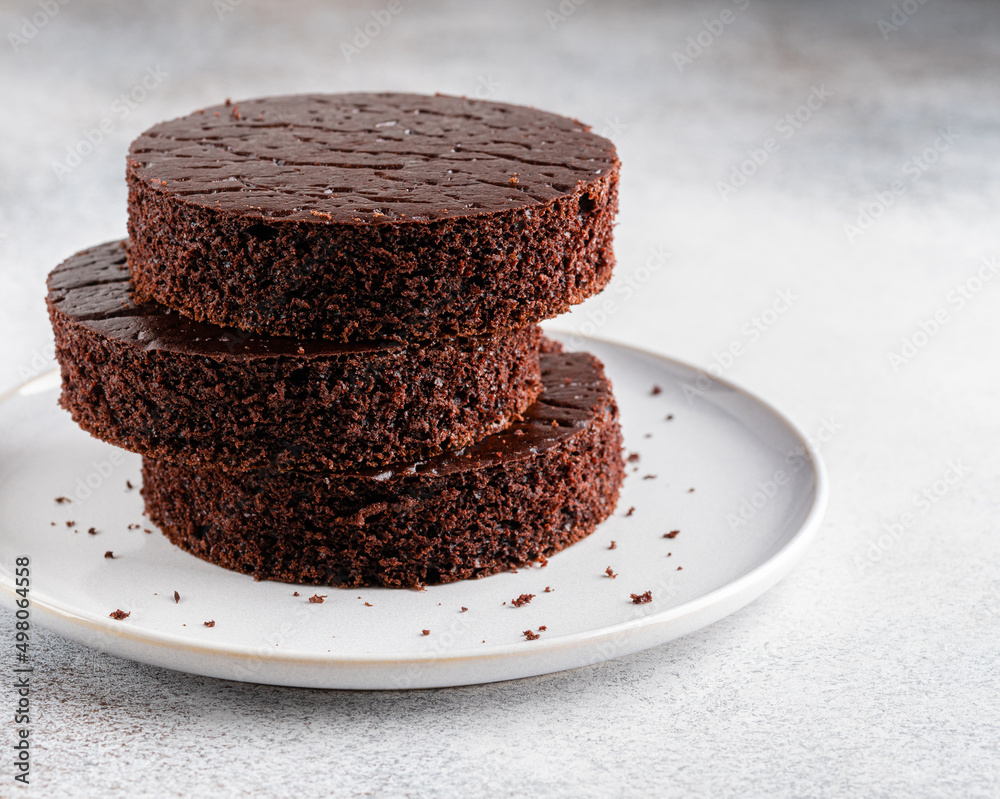 Chocolate sponge cake (biscuit) cut in circle layers stacked on ceramic ...