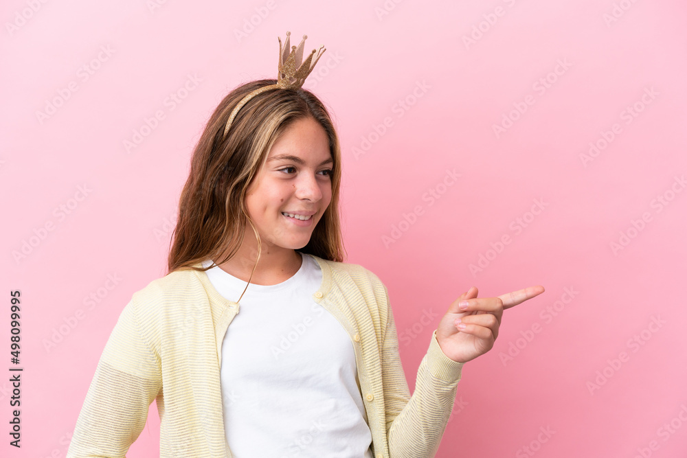 Little princess with crown isolated on pink background pointing finger ...