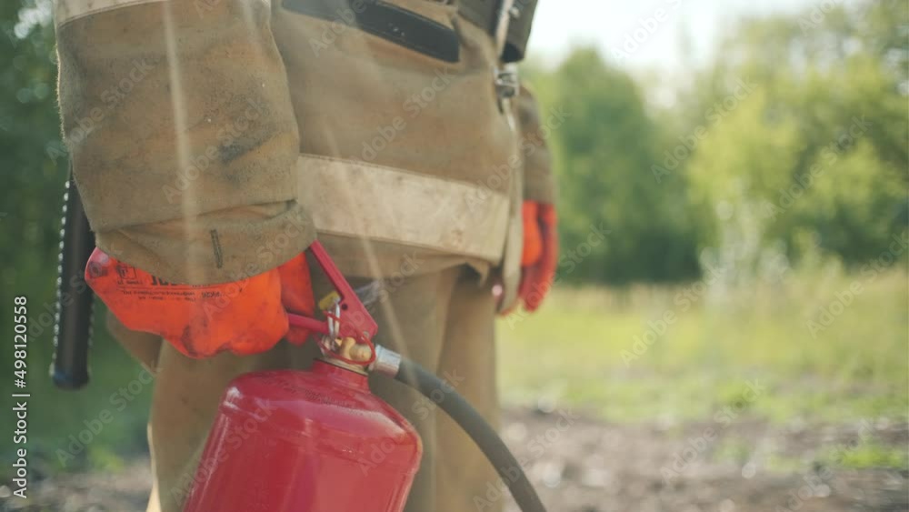 Close up side view of firefighter with a red fire extinguisher in a ...