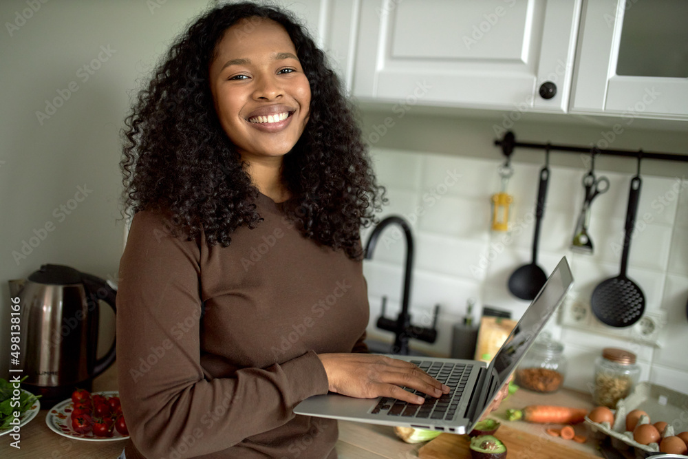 Charming African American woman working in kitchen while cooking ...