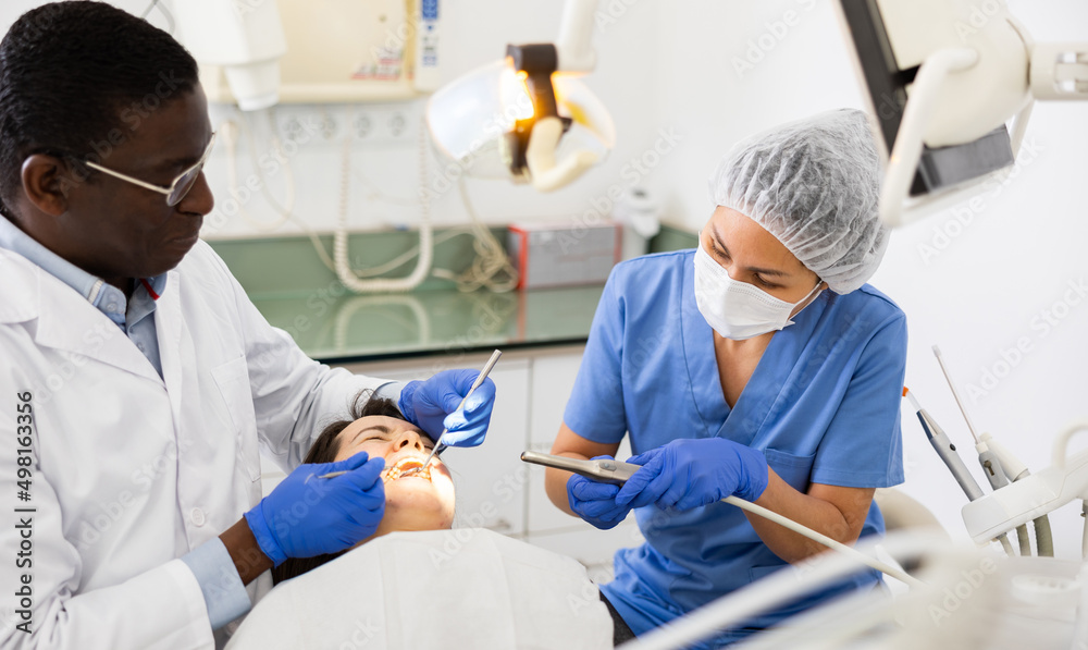 Professional african american dentist performing teeth treatment to ...