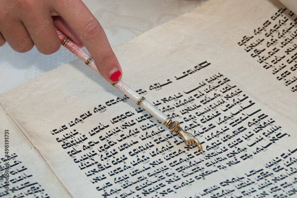 Reading the Torah, the five holy books of Moses and Judaism with the assistance of a pointer or ...