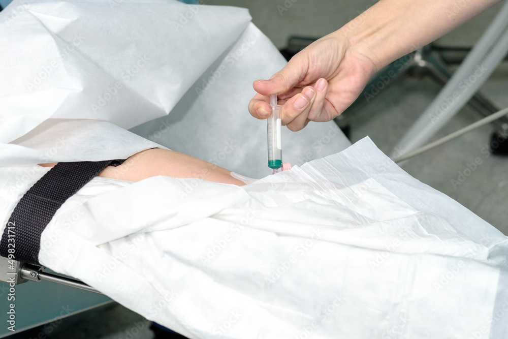 The doctor's hand makes an intravenous injection of medication into the ...
