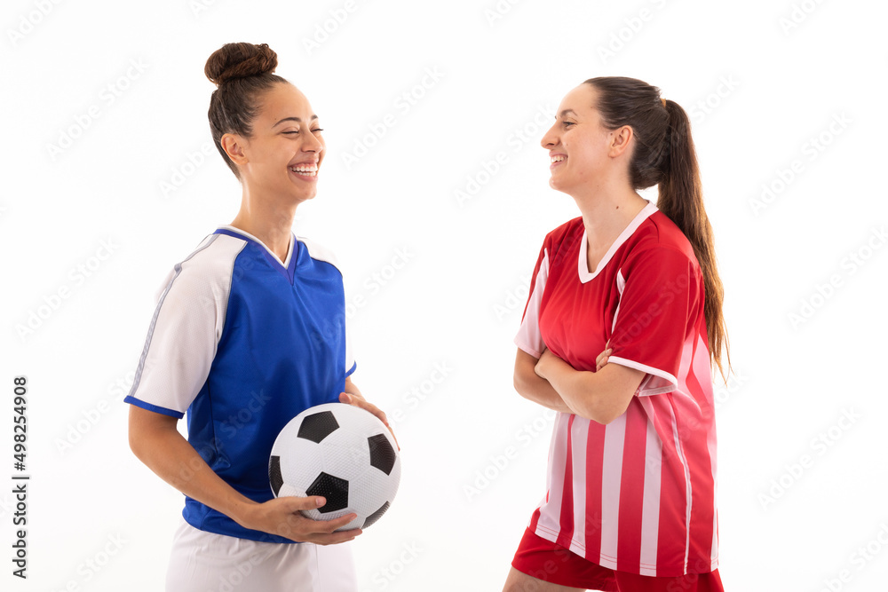 Smiling caucasian and biracial young female soccer players talking ...