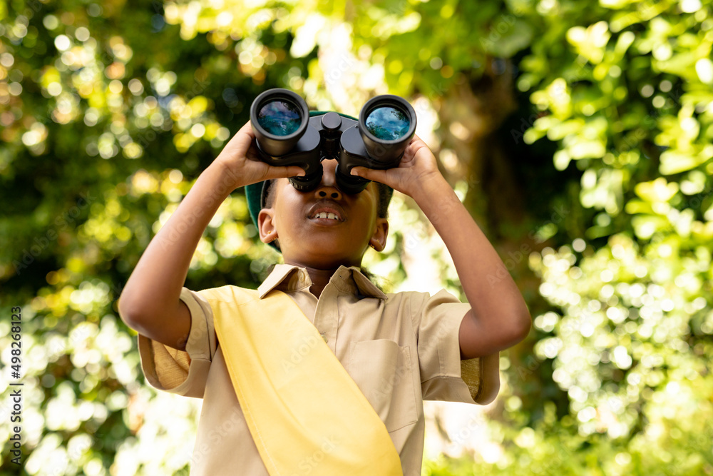 African american scout girl in uniform looking through binoculars while ...