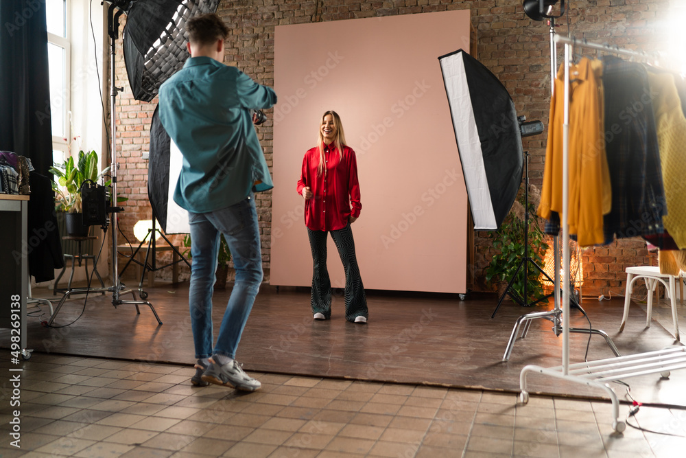 Young photographer taking picures of model, backstage of photoshooting ...