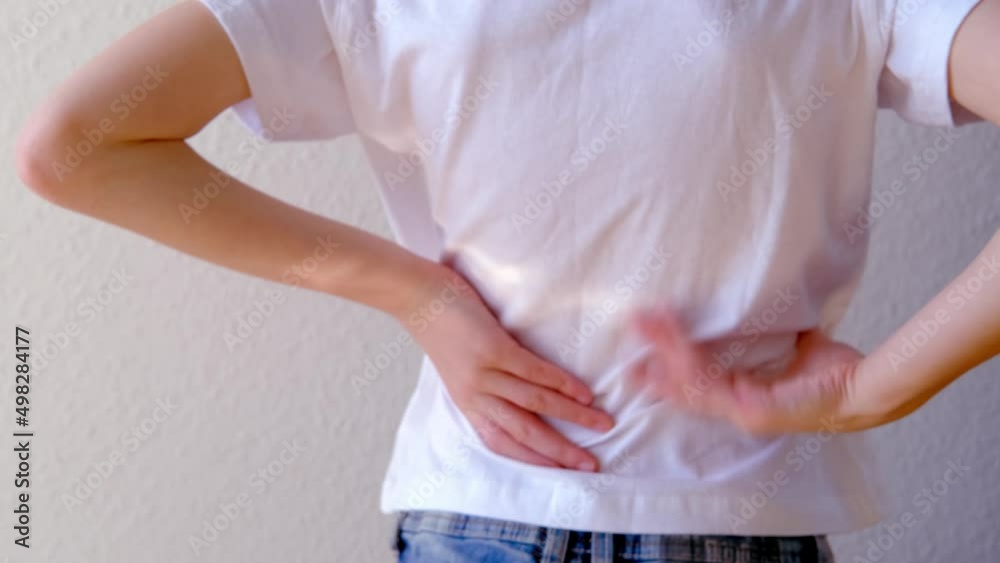 back of boy, child 8-10 years old in a white t-shirt grabbed sore spot ...
