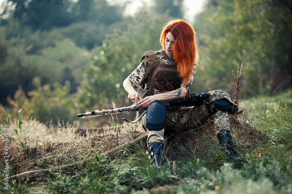 Sniper girl in a green field. Military snipers. The sniper smokes. Red ...