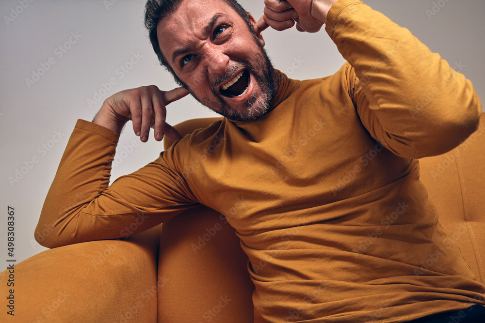 Adult man with furious facial expression while closing his ears. Stock ...