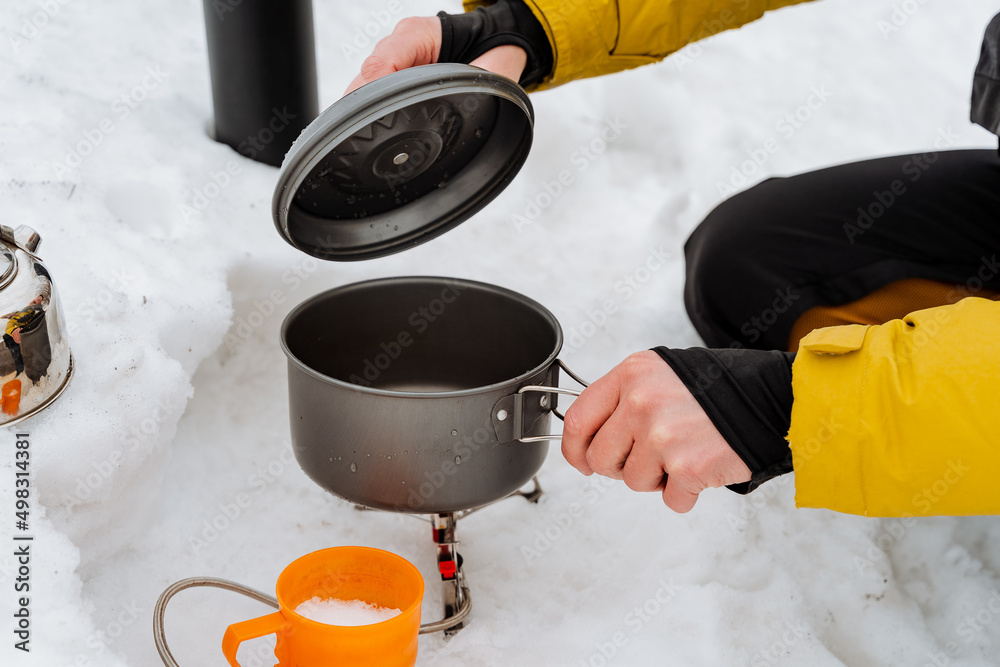 Cooking in nature at the campsite, winter hiking pan stands on the ...