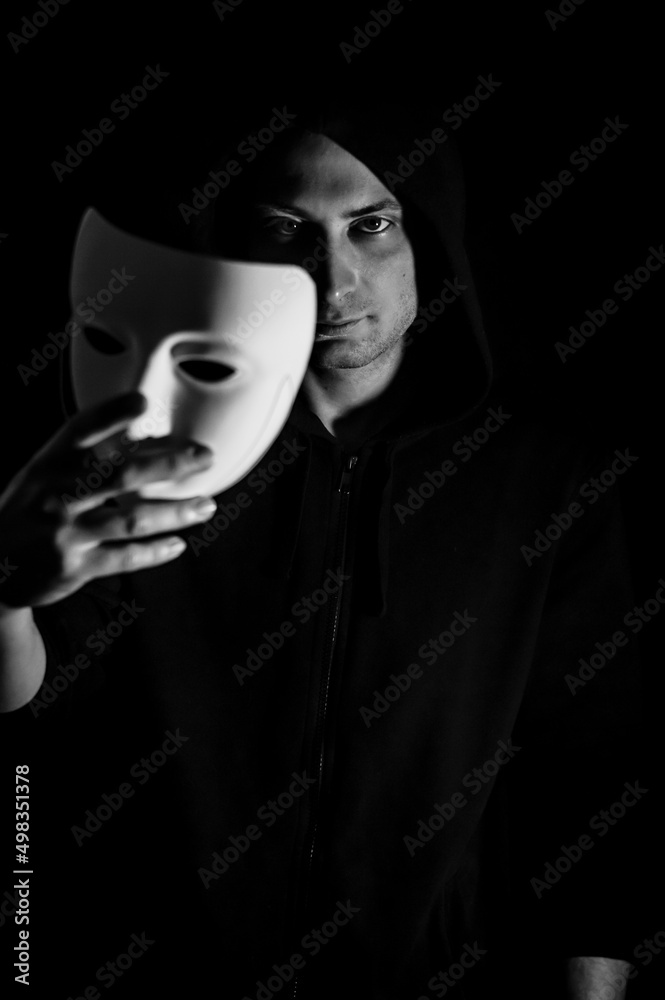Black and white portrait of a young hooded man taking off his mask ...