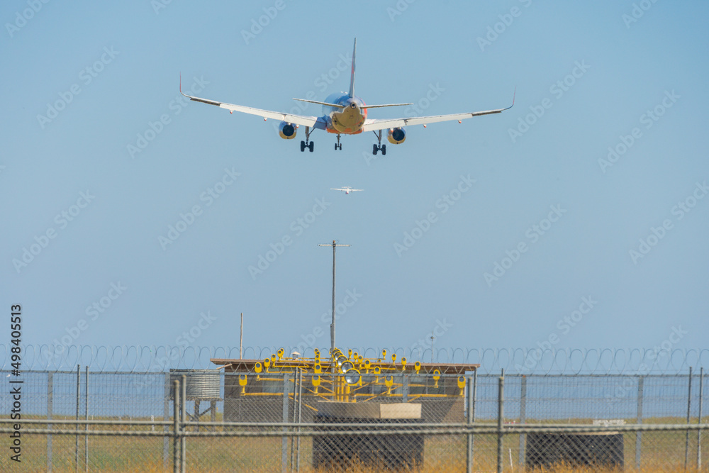 Rear view of a large jet coming into land over runway landing lights ...