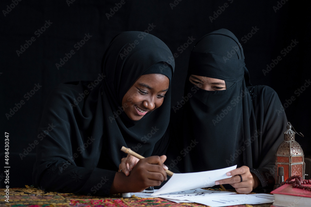 Muslim women wearing black hijab learn to writing Arabic calligraphy ...