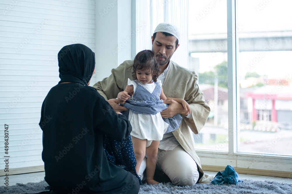 Muslim father and mother in traditional dress helping dressing their ...