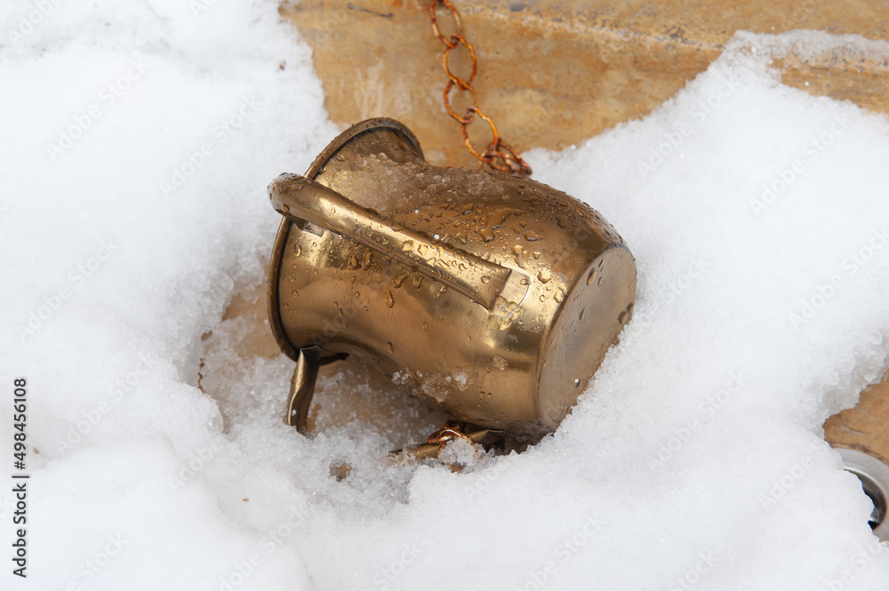 A natla or Jewish ritual hand washing cup lies in a snow-filled sink ...