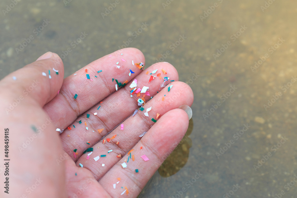 Close-up side shot of hands showing microplastics on the beach ...