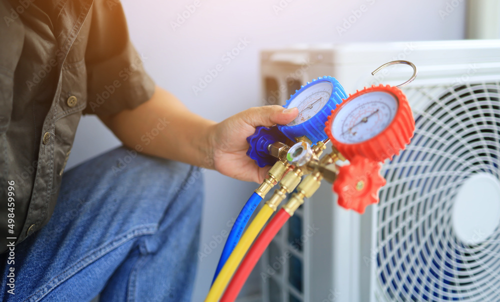 Foto de An air conditioner technician's hand holding a manifold gauge ...