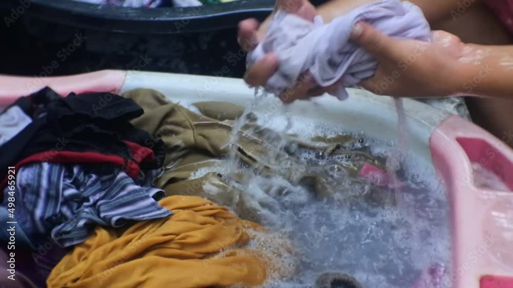 Asian woman washing clothes. Hand washing clothes in a bucket with soap ...