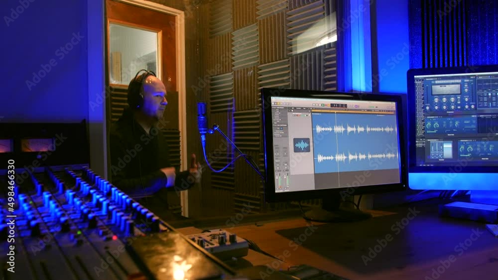 A man is recording a voice over in a recording studio vocal booth ...