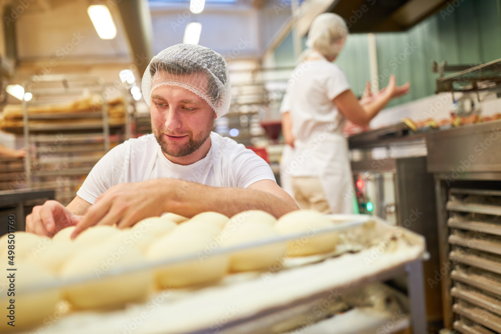 Baker apprentice in training bakes small rolls Stock Photo | Adobe Stock