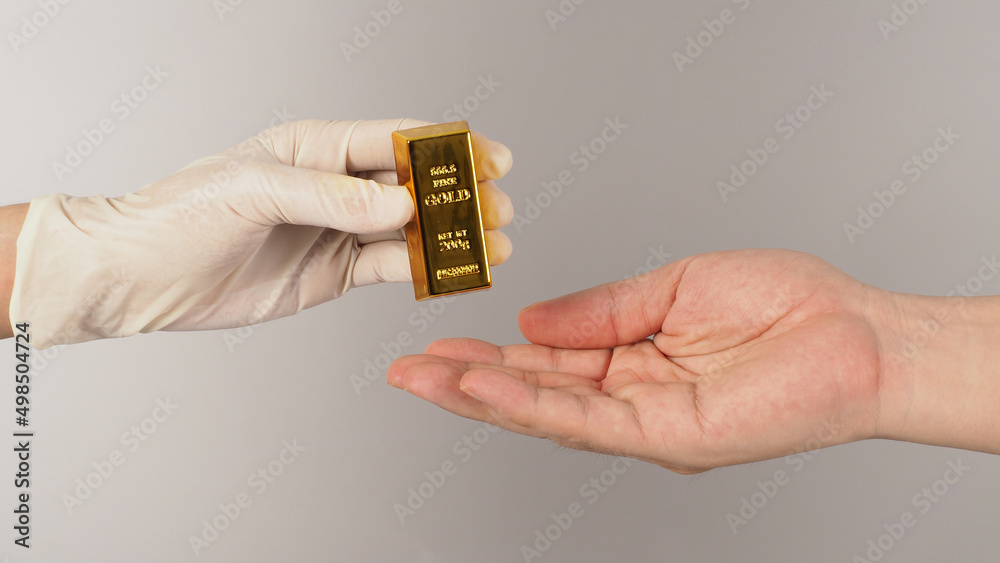 Two hands send and recive gold bar on white background. One Hand wear ...