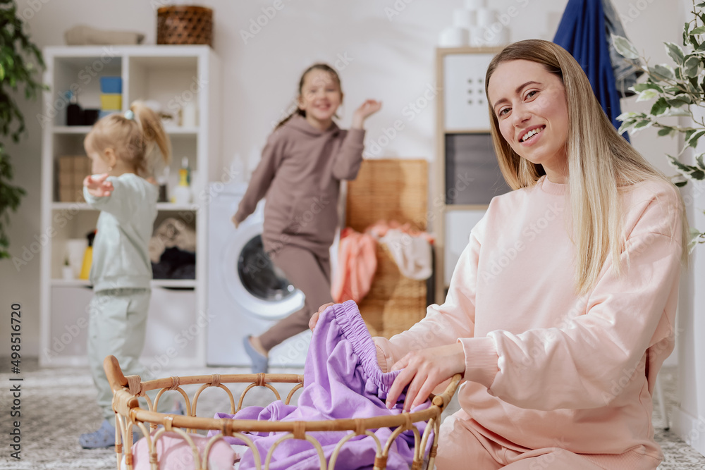 Smiling woman spends time with children while sorting laundry into ...