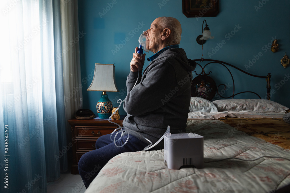 Lateral view angle portrait of an old man with asthma using a nebulizer ...