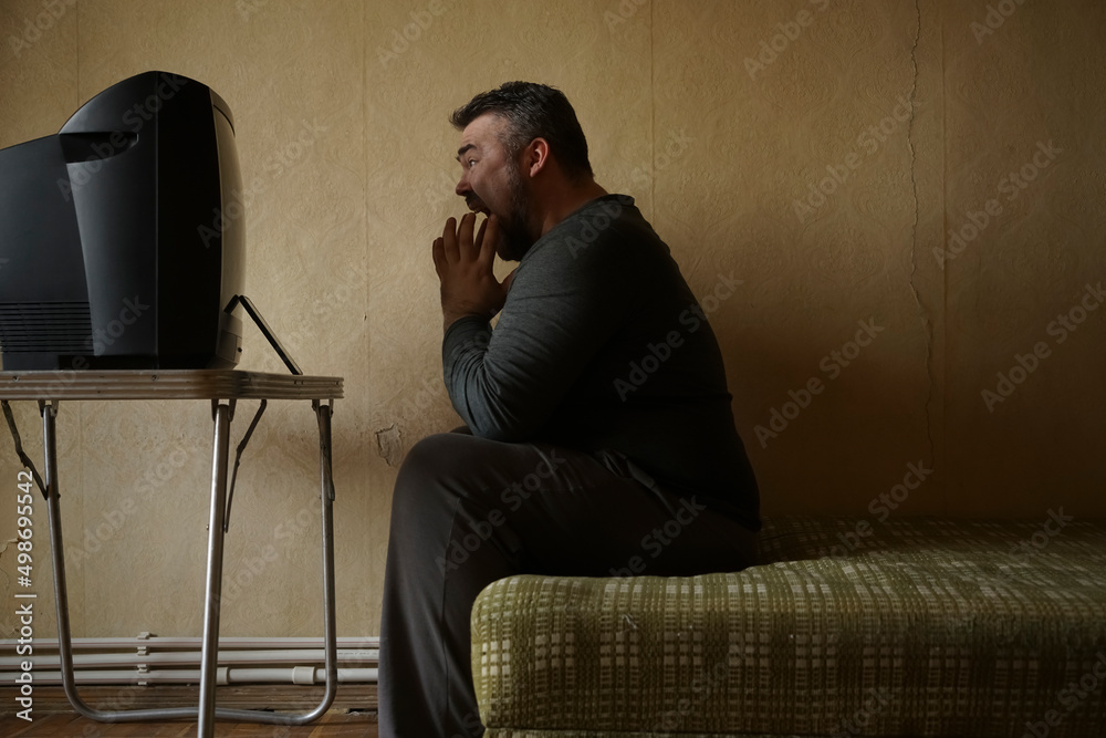 bearded man screaming in shock while watching retro aged tv alone. one ...