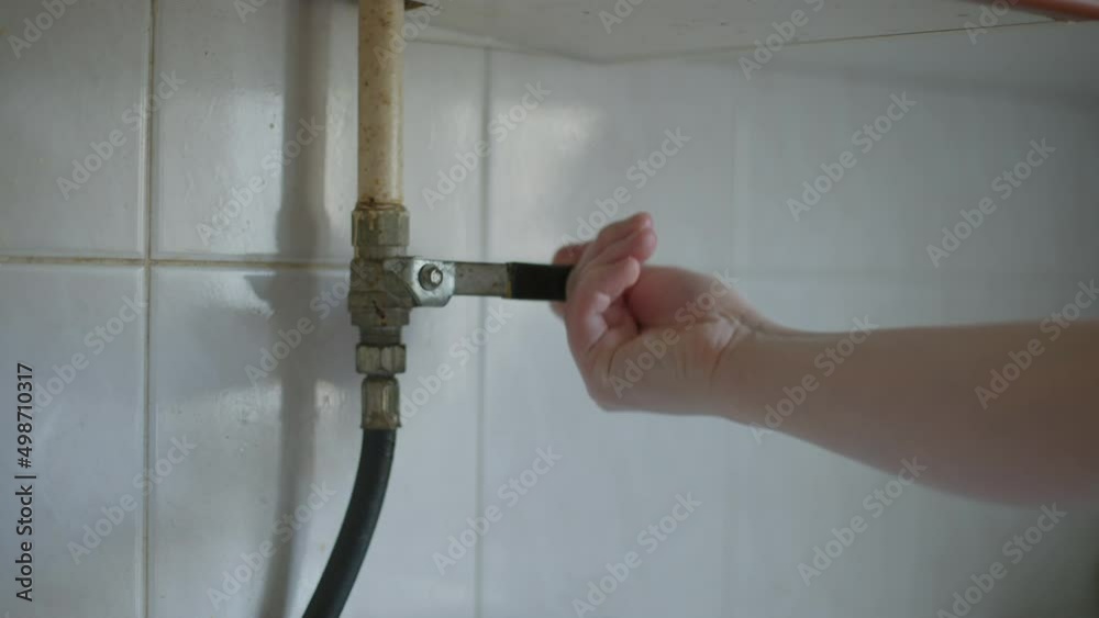 Female Caucasian hand turning off water pipe indoors at home ...
