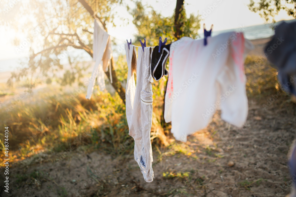 Linen clothes are dried on a rope among trees, sand and beach and ...